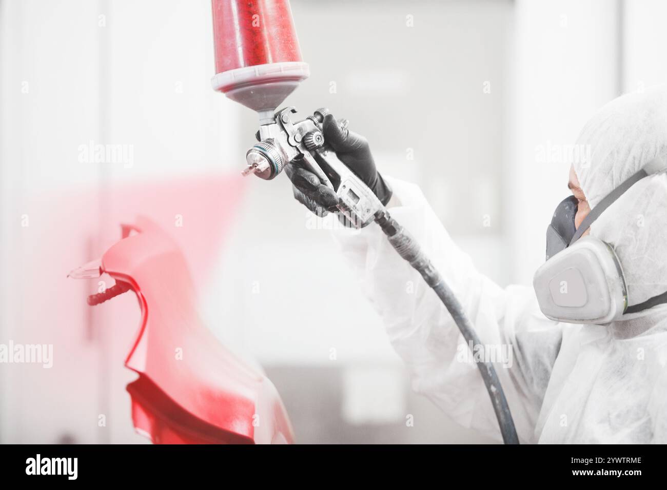 Professional male car painter is painting in garage by airbrush. Man ...