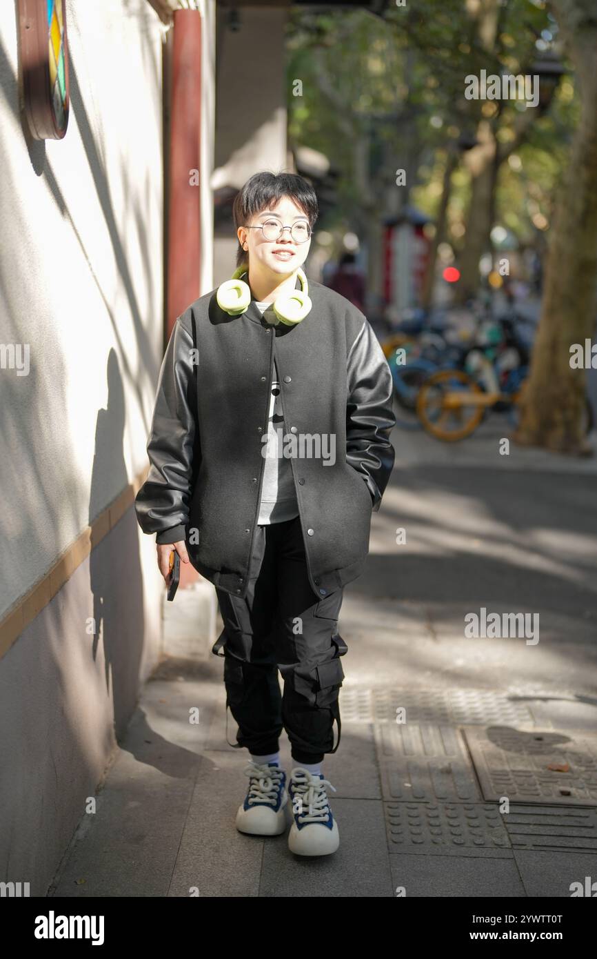 A Chinese woman in her 30s in sporty clothes walks along Jilu Road in ...