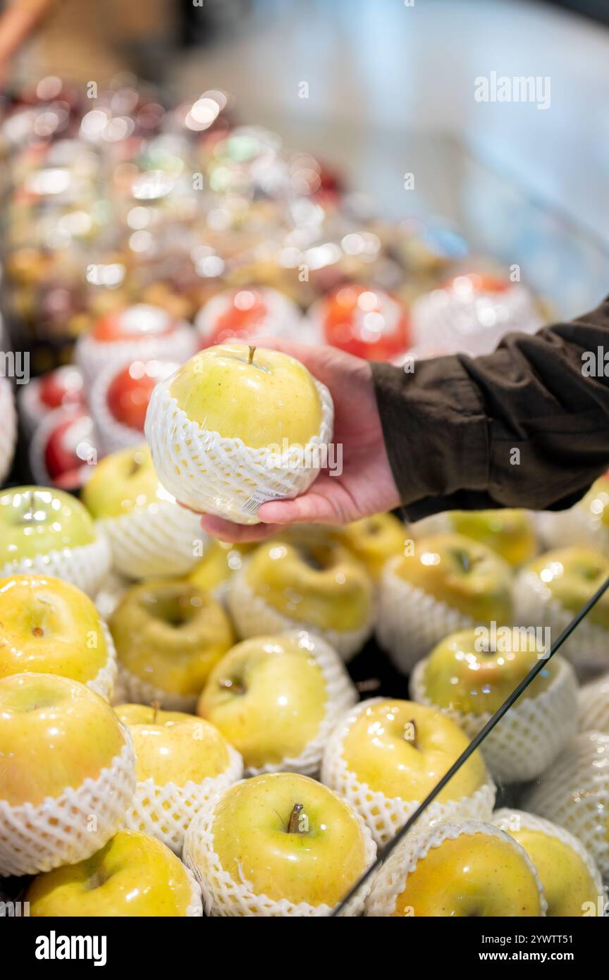 A close-up of a man's hand selecting fruit from a fruit cart while ...