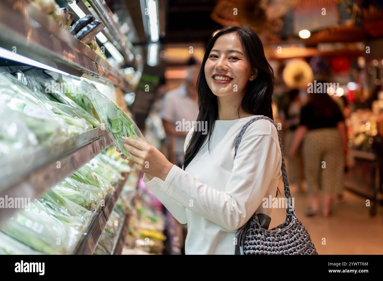 A beautiful Asian woman grocery shopping at a supermarket, selecting ...
