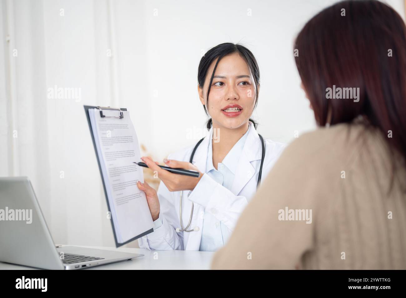 A confident Asian female doctor showing a medical paper to a patient ...