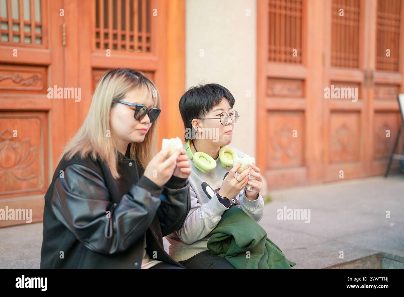 Two Chinese women in their 30s eating steamed buns in front of ...