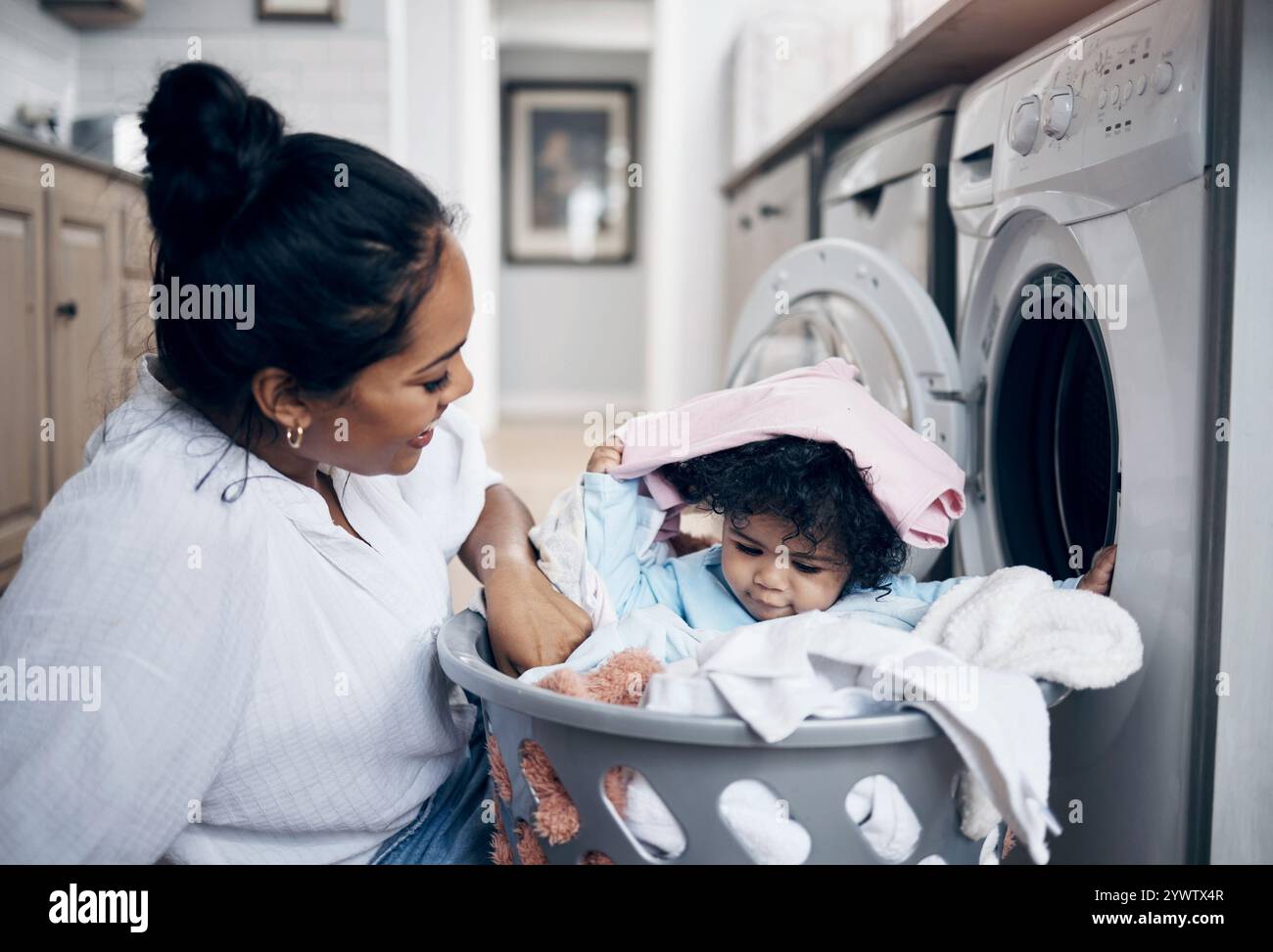 Mother, baby and playing with laundry in home, helping mom and ...