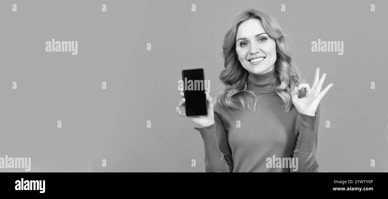 Approved mobile phone. Happy girl show OK sign to smartphone. Approved ...