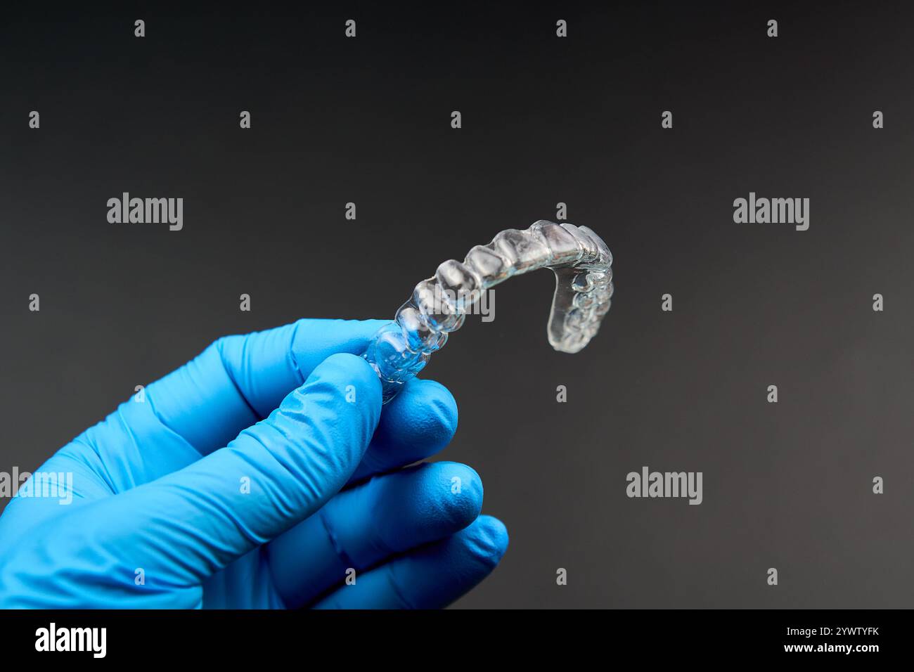 In their hand, a person wearing blue gloves is holding a clear brace ...