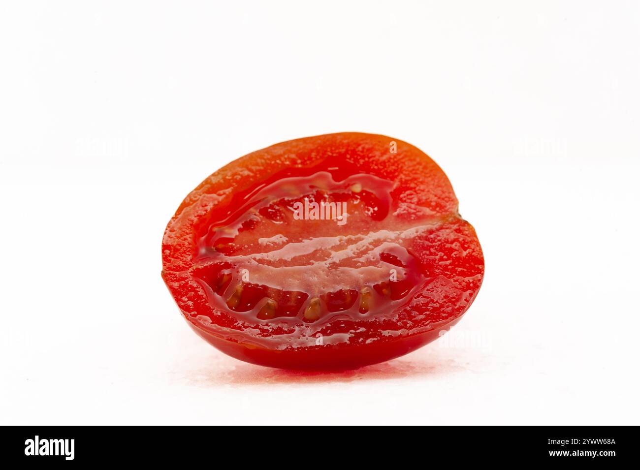 A tomato is cut in half and the inside is shown. The tomato is red and ...