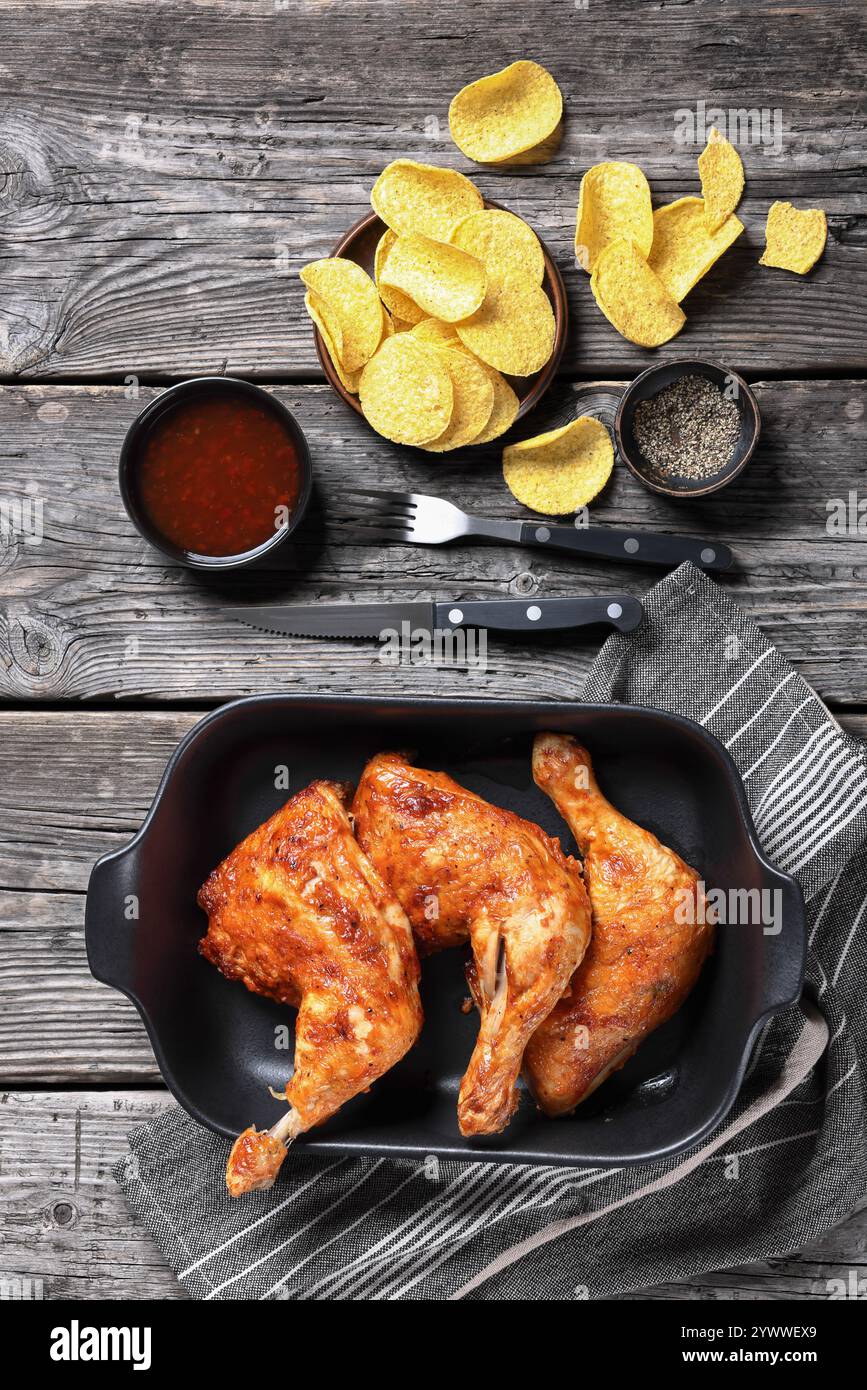 baked in oven three chicken leg quarters in black baking dish on grey ...