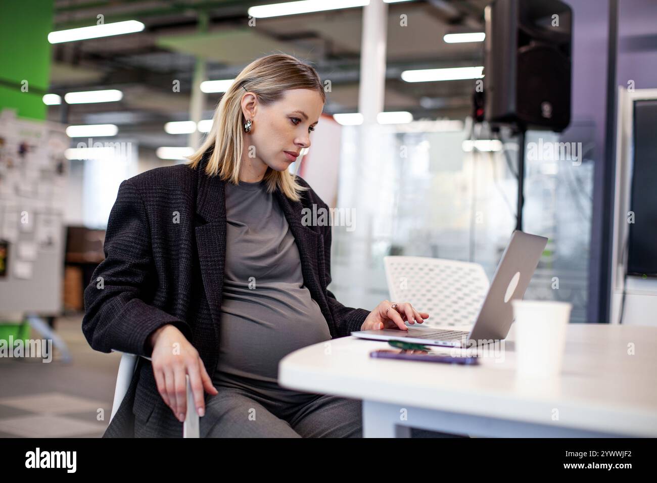 Confident pregnant female executive efficiently works on her computer ...