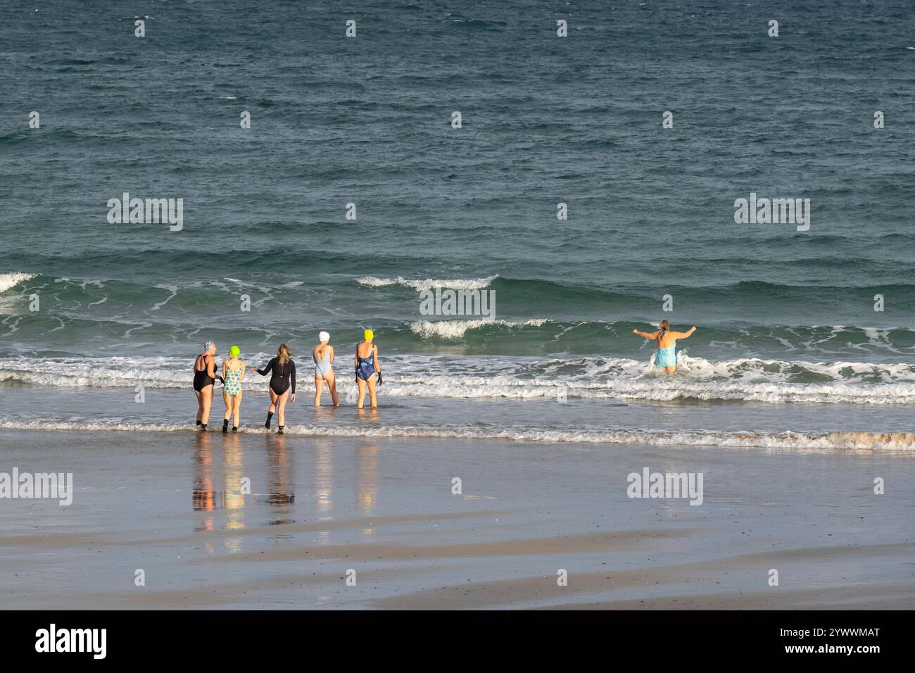 A group of female cold water swimmers walking into the sea for an early ...