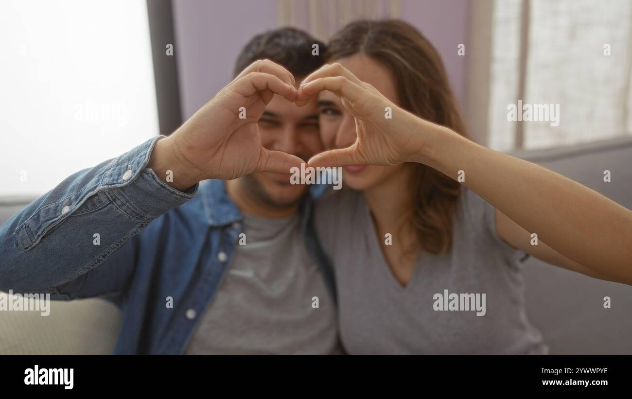 Couple showing love sign with hands while sitting together in a cozy ...