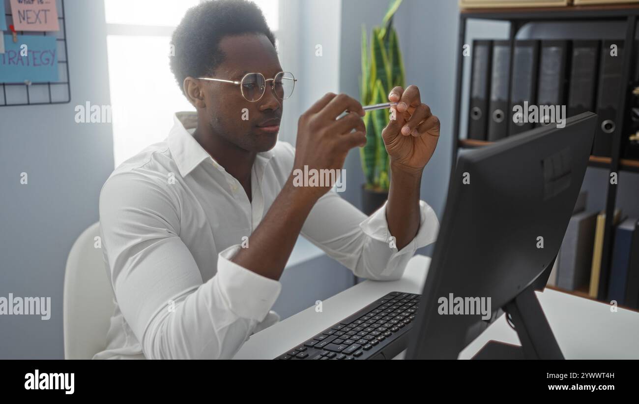 Young man working in a modern office, focusing intently on a pen while ...
