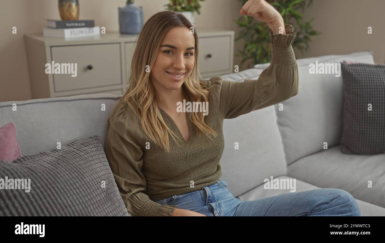 A beautiful young adult woman makes a strong arm gesture while sitting ...