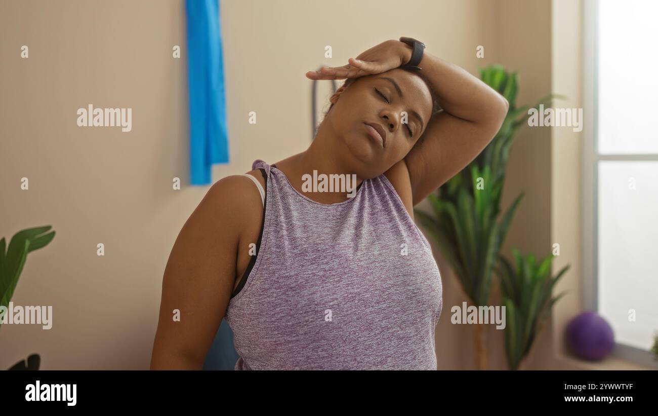 Woman stretching indoors in a gym, wearing workout clothes and a ...