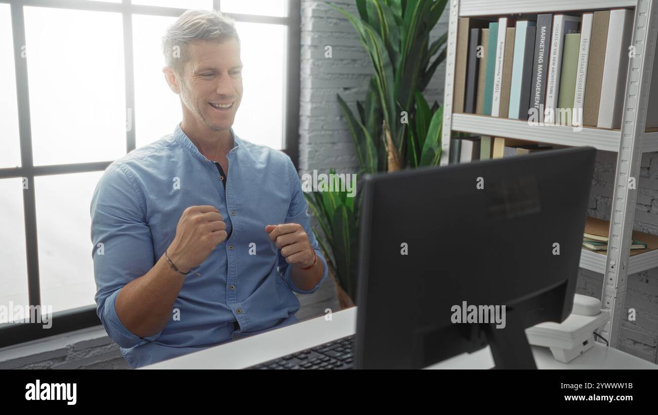 Young man smiling at computer in modern office setting showcases ...
