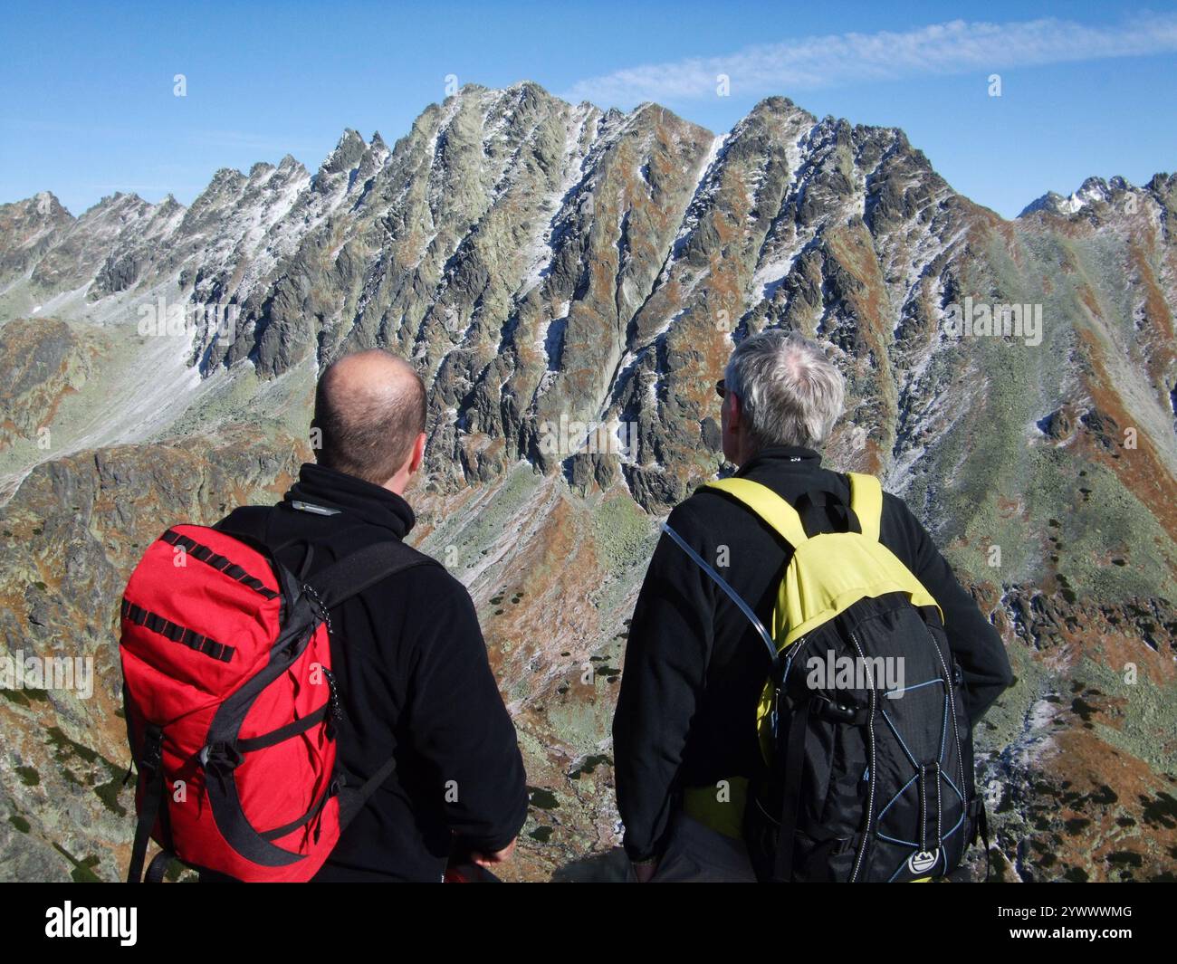 Two men or walkers with backpacks admiring the iew of mountain peaks in ...
