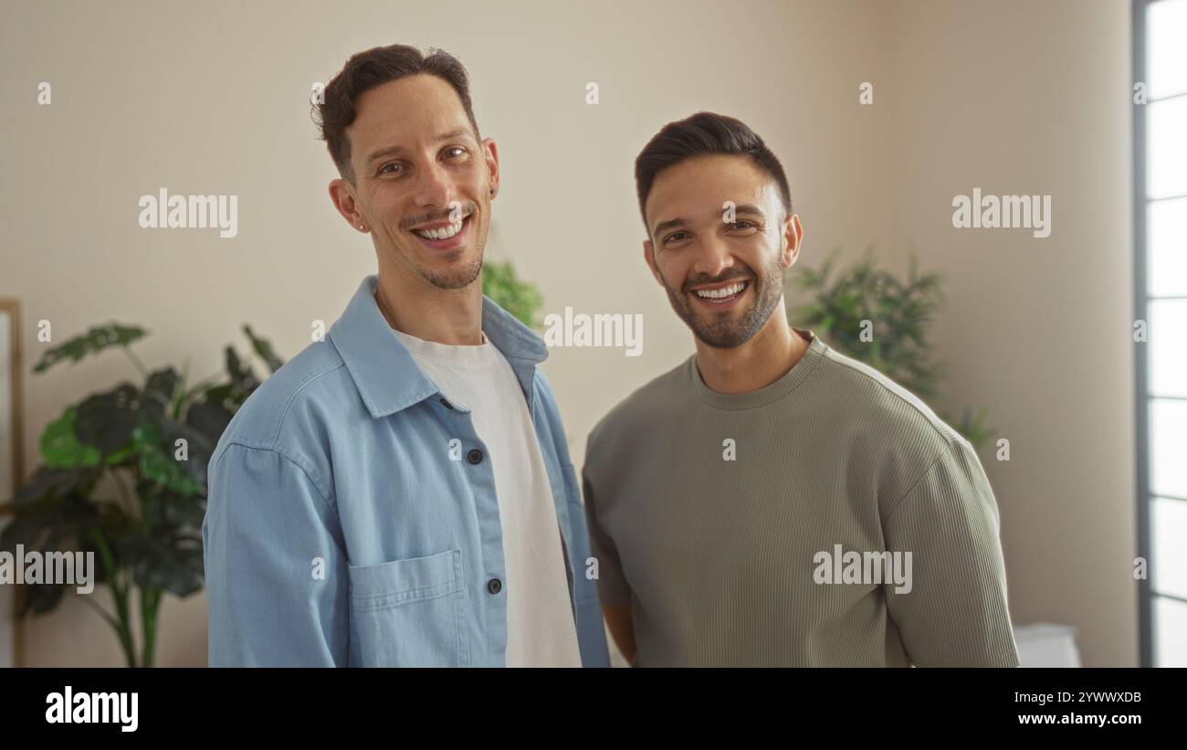 Happy couple of two men standing together in a bright living room ...