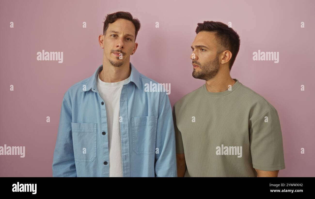 Two men standing together against a pink background, representing a gay ...