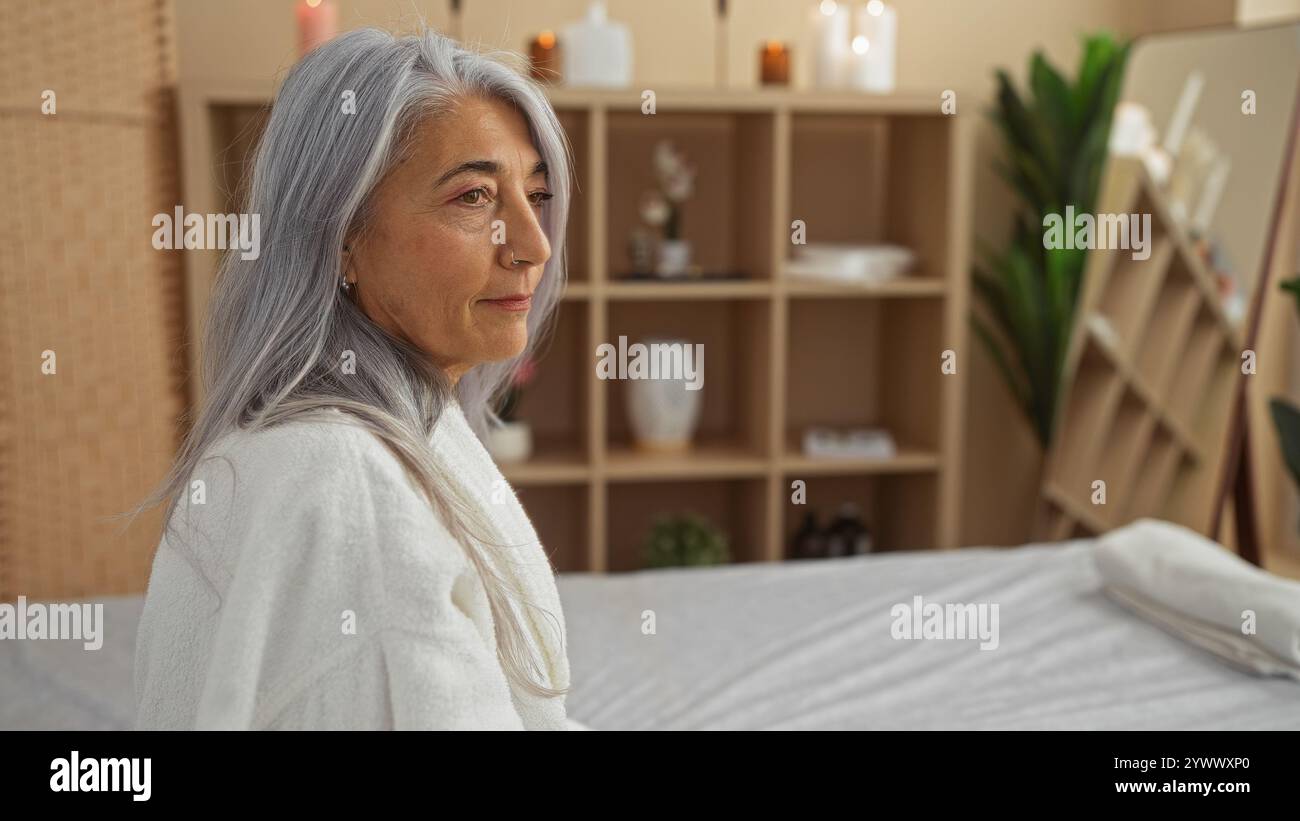 Woman with grey hair in a serene spa room with candles, wearing a white ...