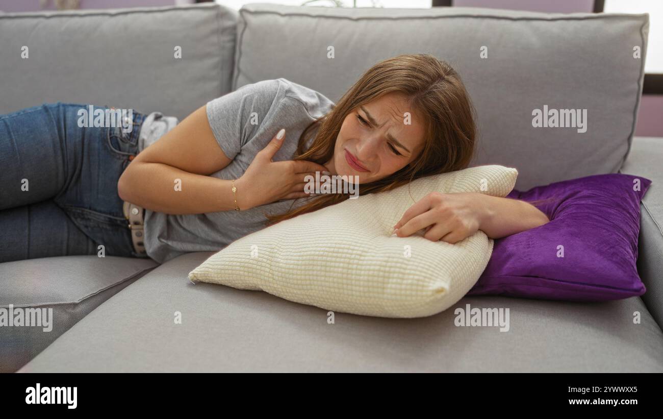 Woman lying on sofa in living room appears unwell holding chest and ...