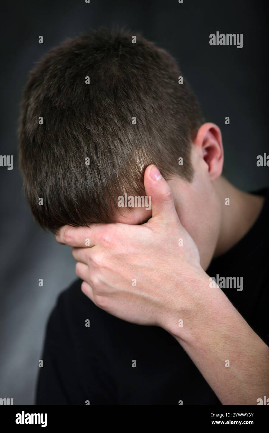 Sad Young Man On the Black Background hide his Face Stock Photo - Alamy