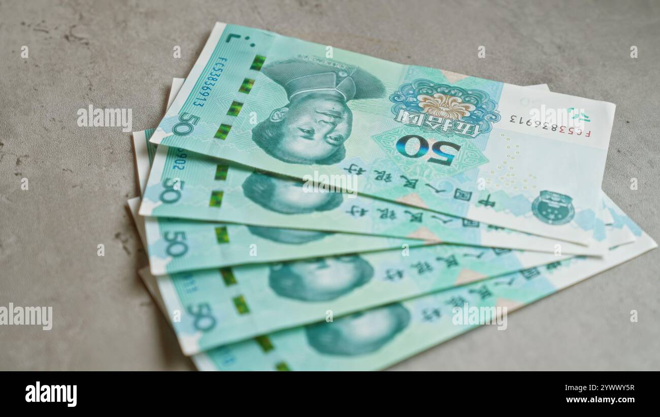Chinese yuan banknotes laid out on a concrete surface representing ...