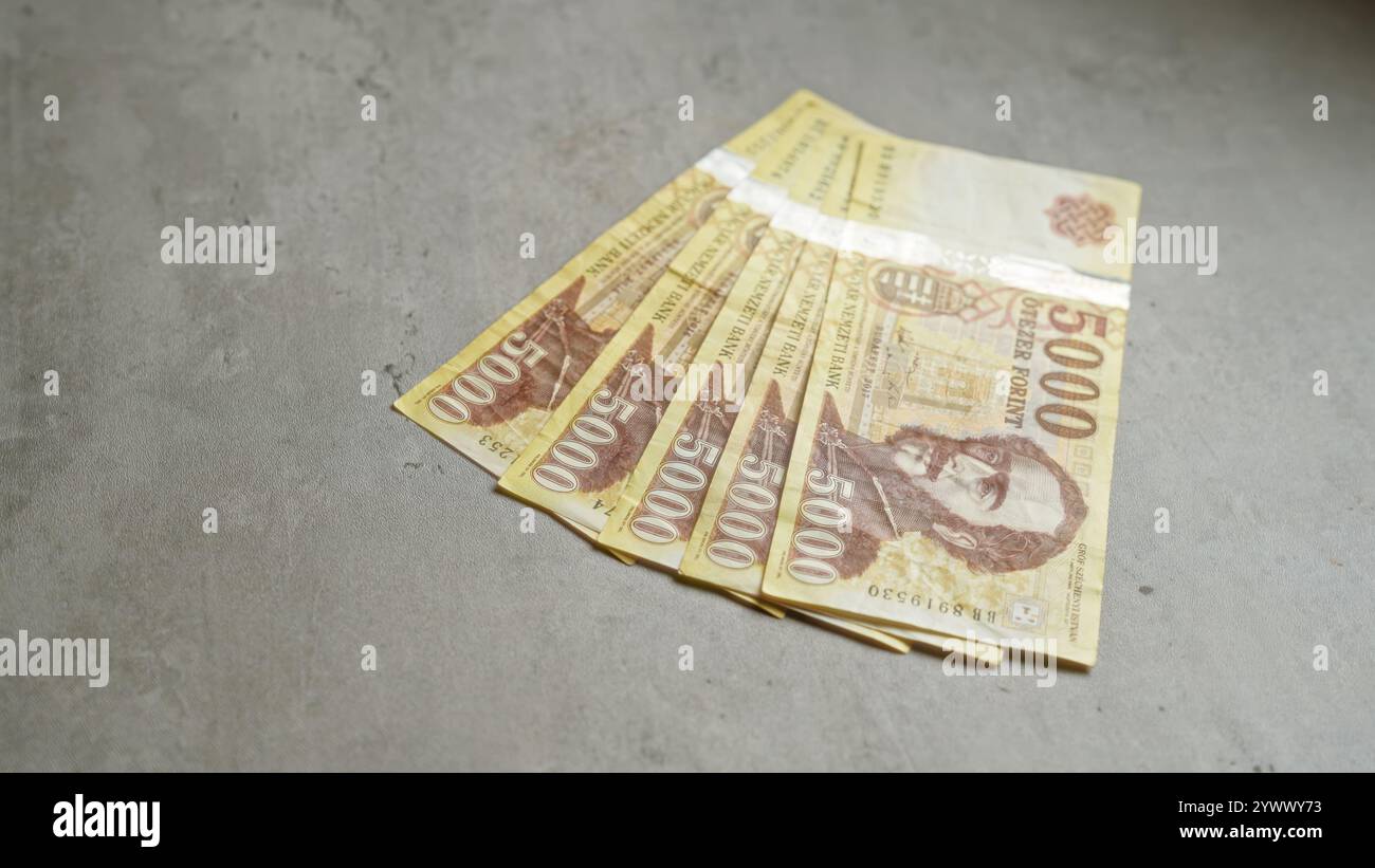 Hungarian 5000 forint banknotes spread out on a concrete surface ...