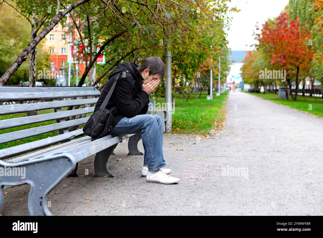 Sad young man sitting on the bench outdoor Stock Photo - Alamy