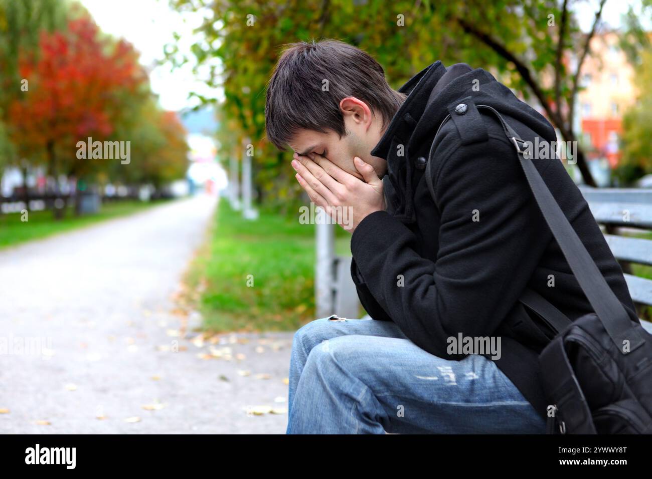 Sad young man sitting on the bench outdoor Stock Photo - Alamy