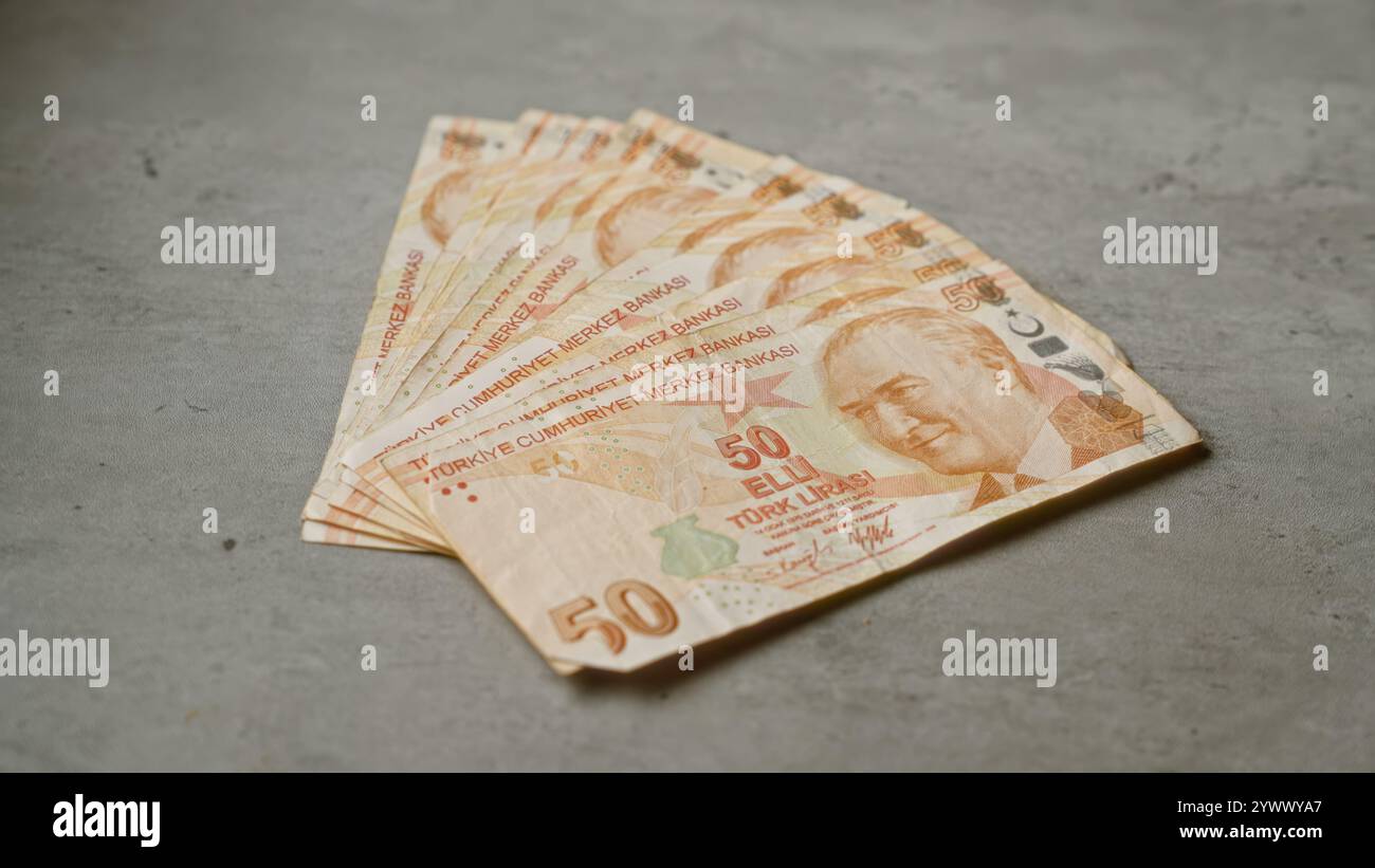 Turkish banknotes of fifty lira are arranged spread out on a concrete ...