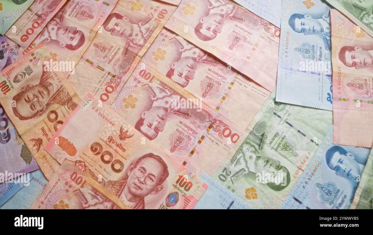Various colorful thai baht banknotes from thailand are scattered in a ...