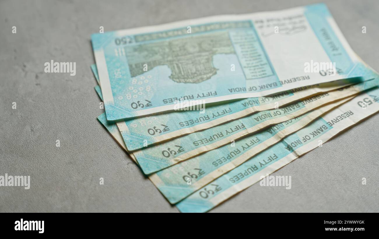 Indian fifty rupee banknotes displayed on a concrete surface indicating ...