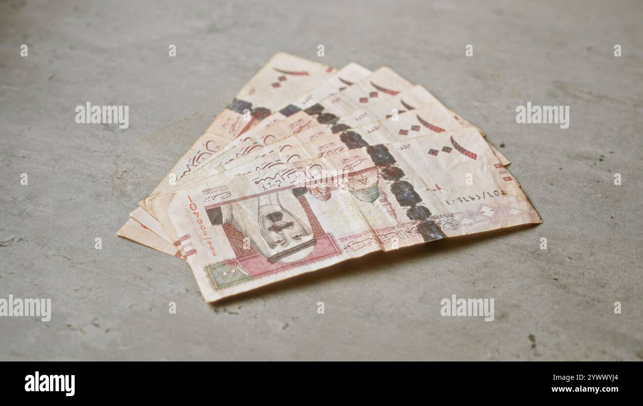 Saudi riyals banknotes spread on a concrete surface, representing ...