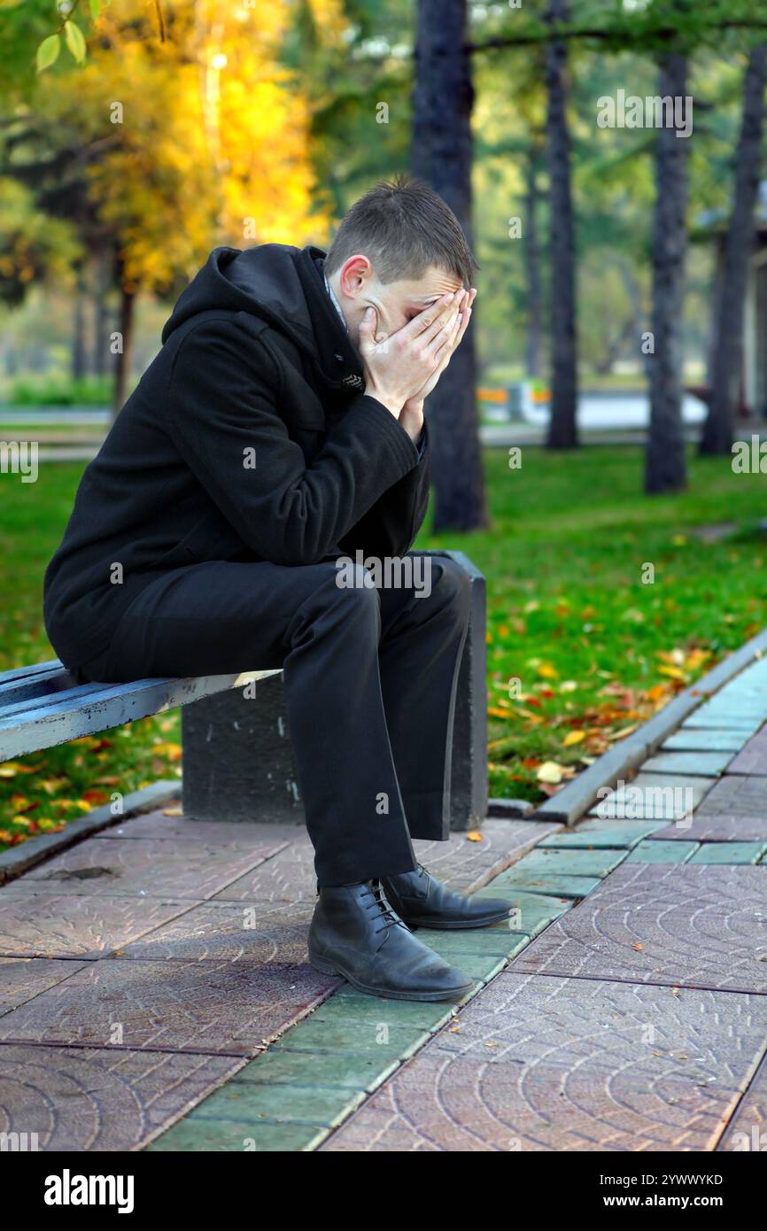 Sad young man sitting on the bench outdoor Stock Photo - Alamy