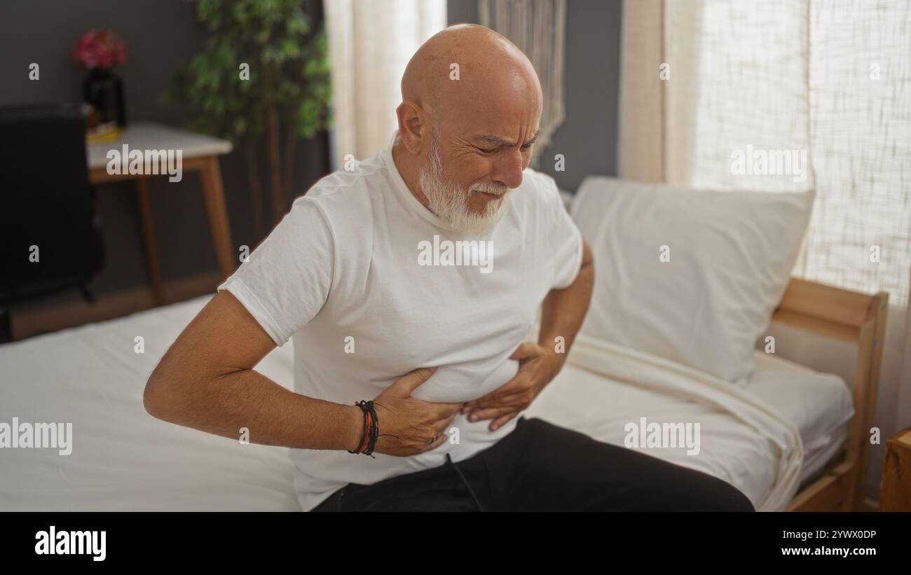 Man experiencing chest pain sitting on bed in bedroom with hands ...