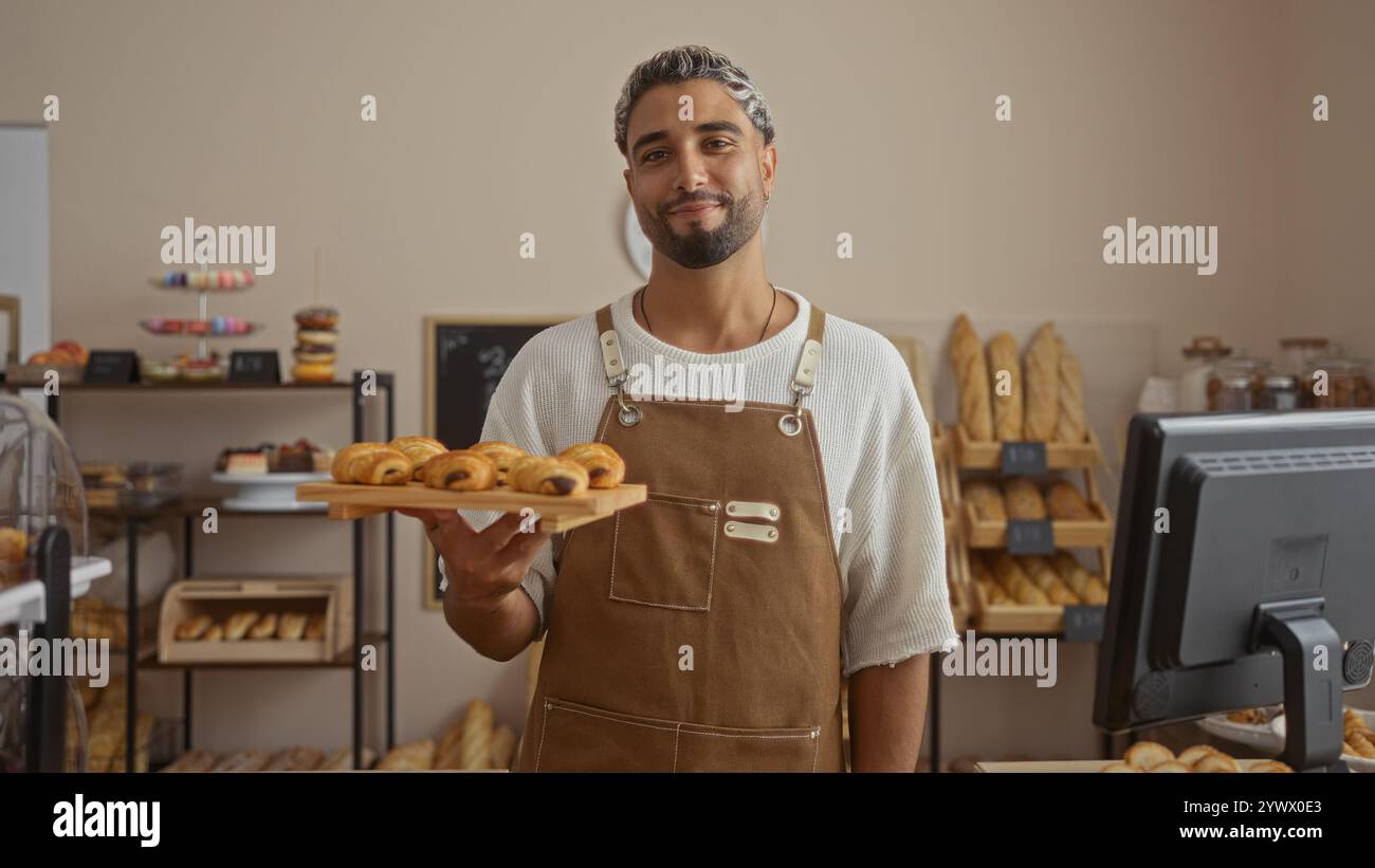Handsome young arab man with a beard holding a tray of pastries in a ...