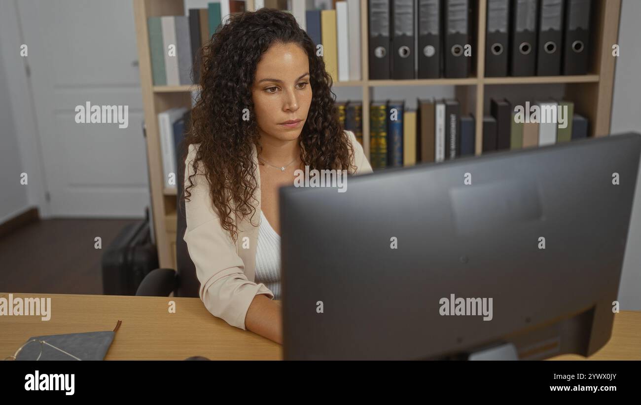 Young woman working in an office with bookshelves and binders in the ...