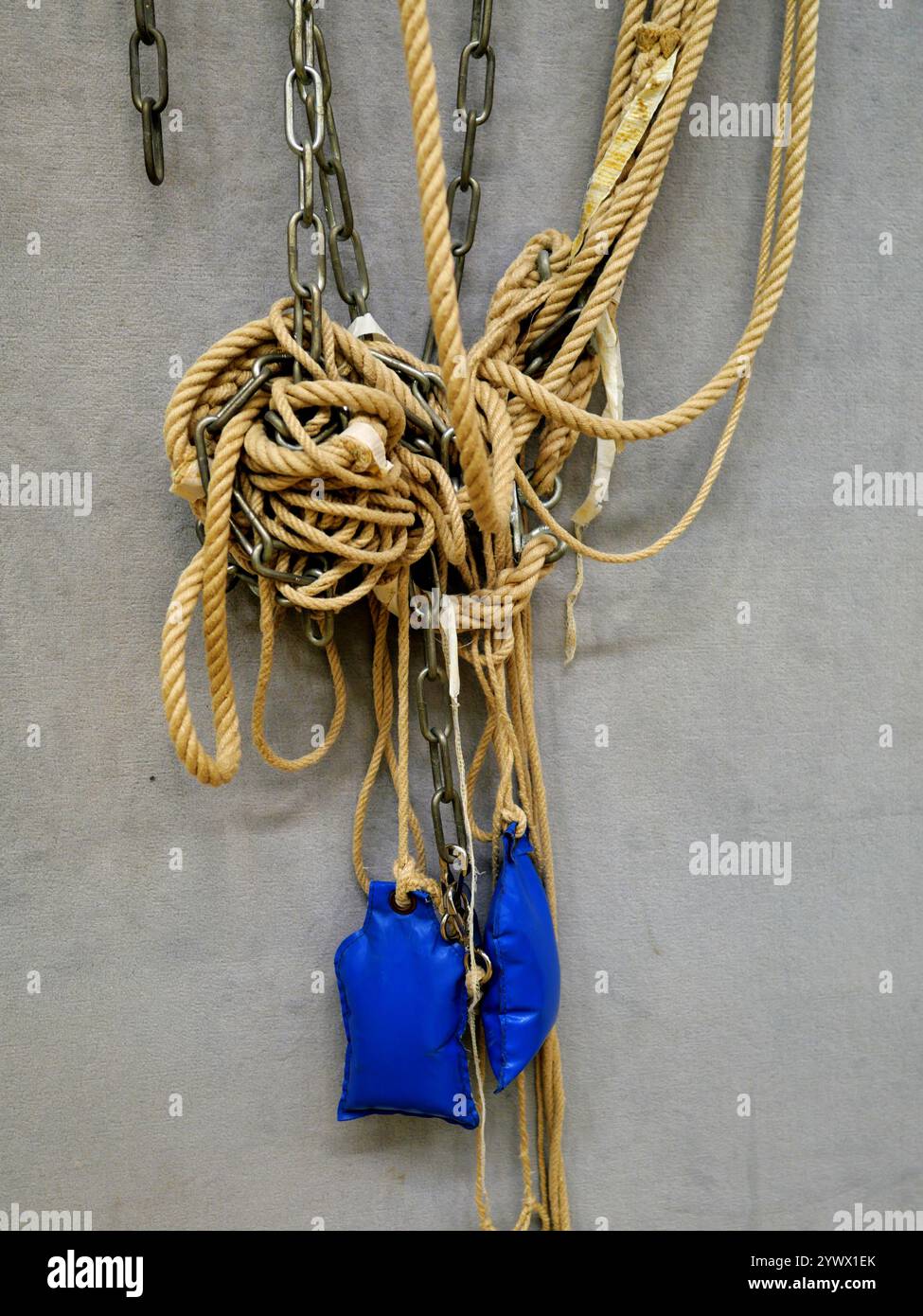 Tangled ropes and chains on a sports hall wall create a chaotic yet ...