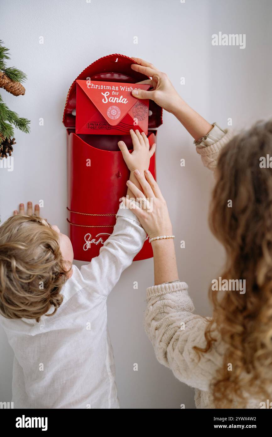 Child placing letter in Santa's mailbox for Christmas wishes during ...