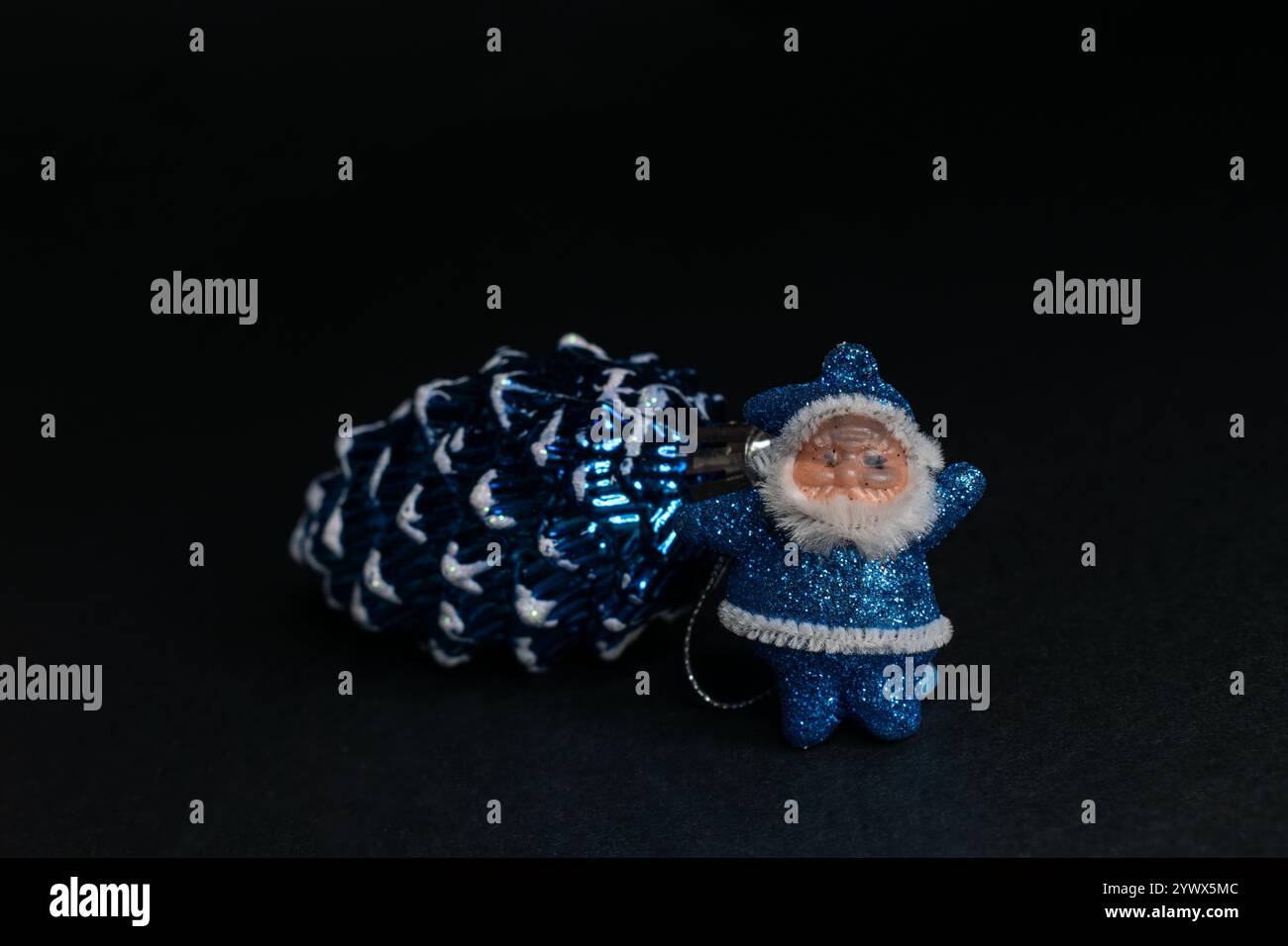 Small blue santa claus with blue pine cone bauble isolated on a black ...