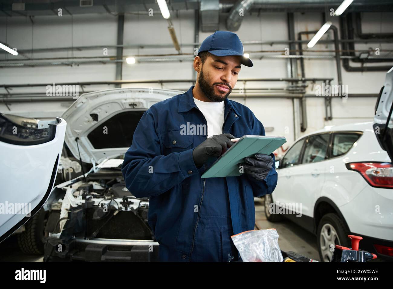 Handsome mechanic inspects vehicle information while working in a ...