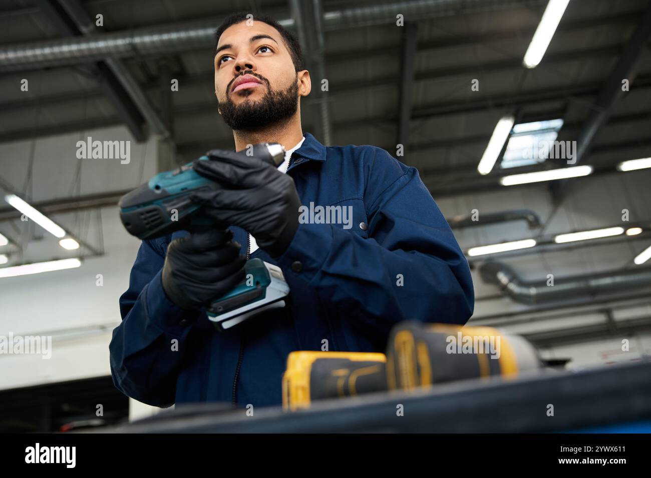 Mechanic demonstrates skills while holding tools in a well lit ...