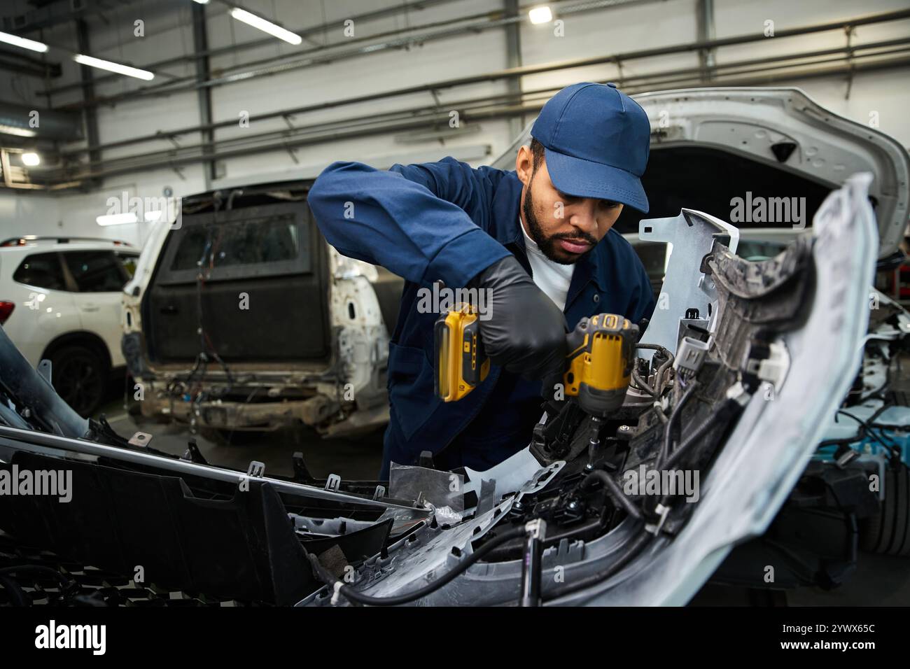 Young mechanic focuses intently while repairing car parts in a bustling ...