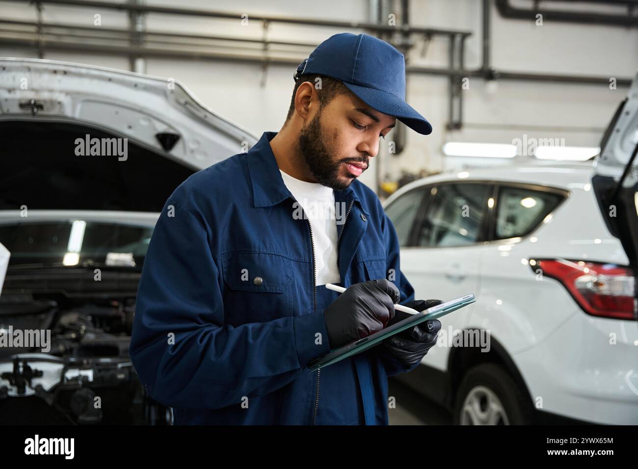 Young mechanic checks vehicle diagnostics with focus in a bustling ...