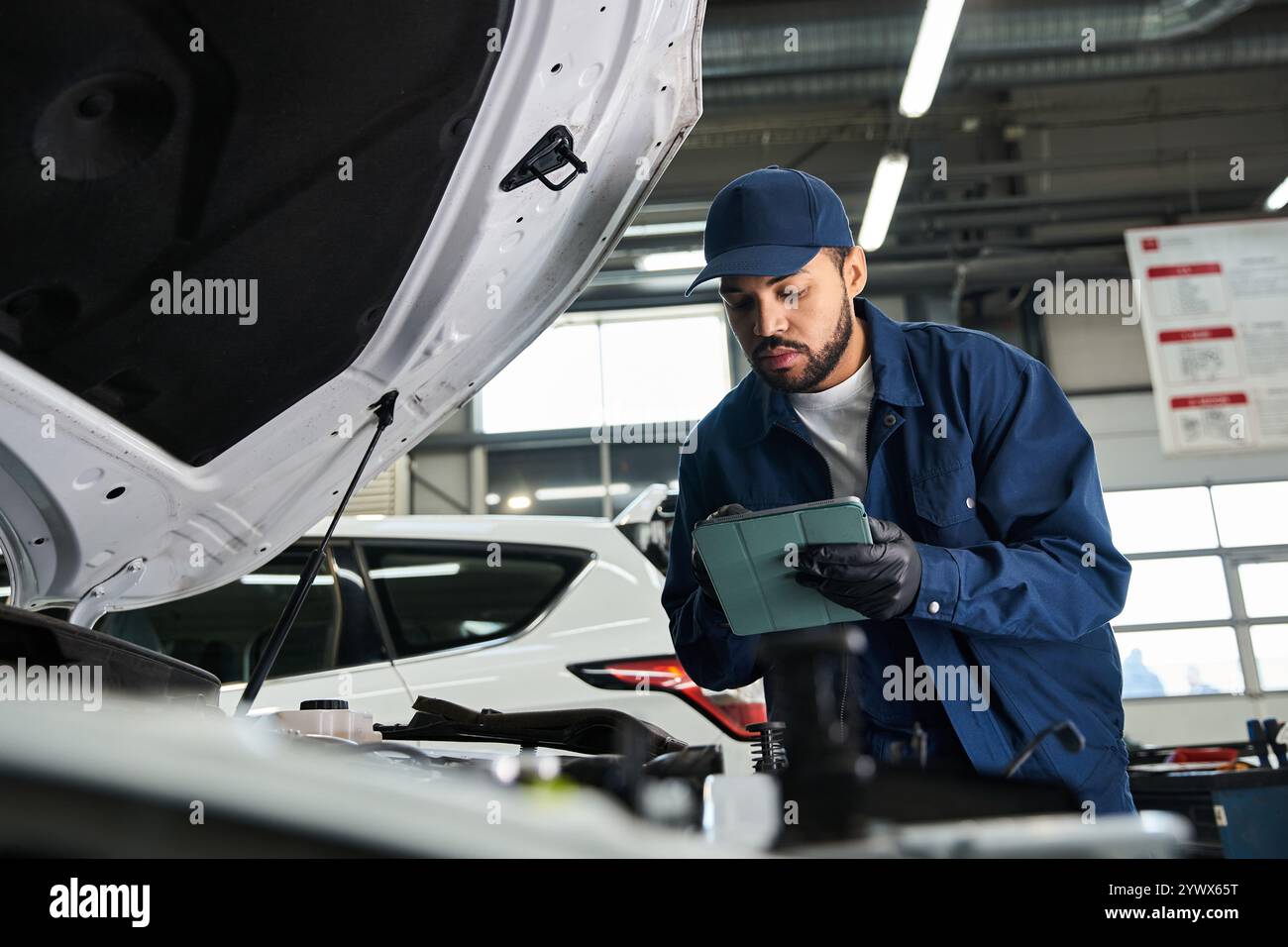 Young mechanic intently checks vehicle diagnostics in the garage Stock ...
