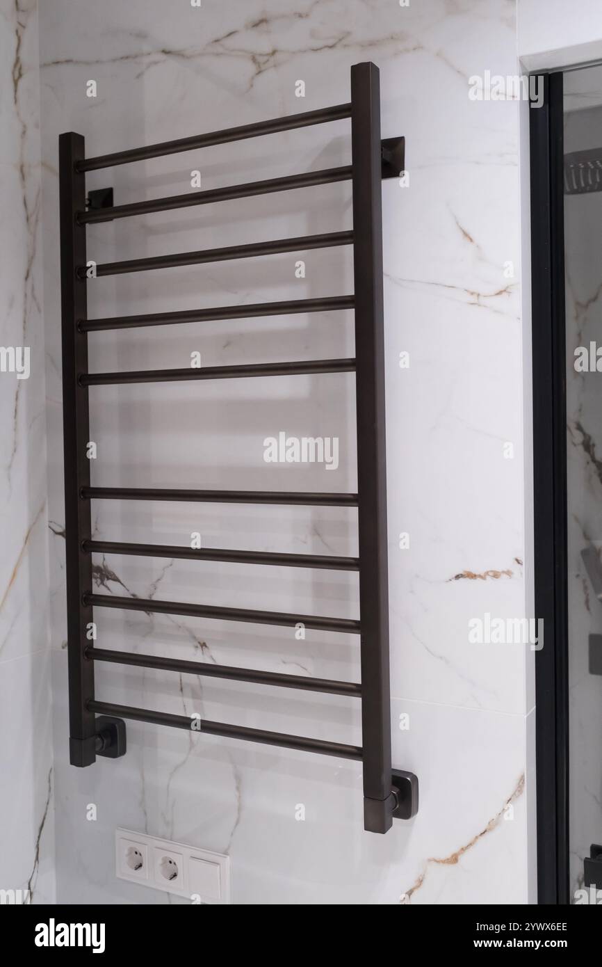 Modern black radiator on white marble wall in bathroom. New bathroom ...