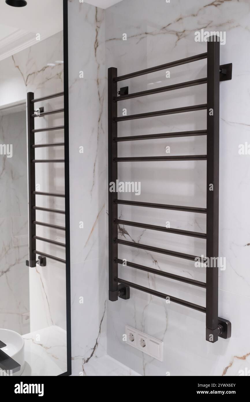 Modern black radiator on white marble wall in bathroom. New bathroom ...