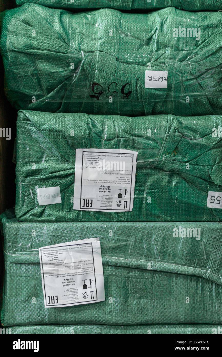 In the warehouse, there are stacked green wrapped packages organized ...