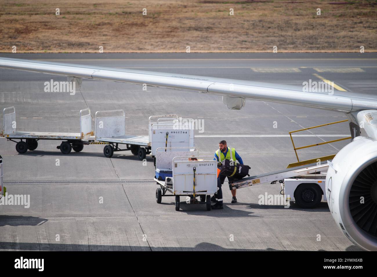 Airport ground crew man loading luggage suitcases onto a plane from ...