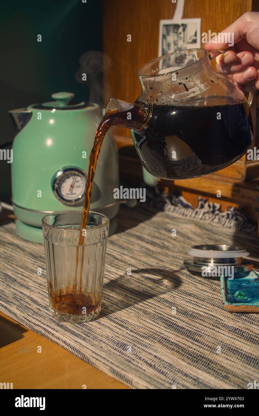 Pouring a cup of freshly brewed aromatic coffee into a clear, elegant ...