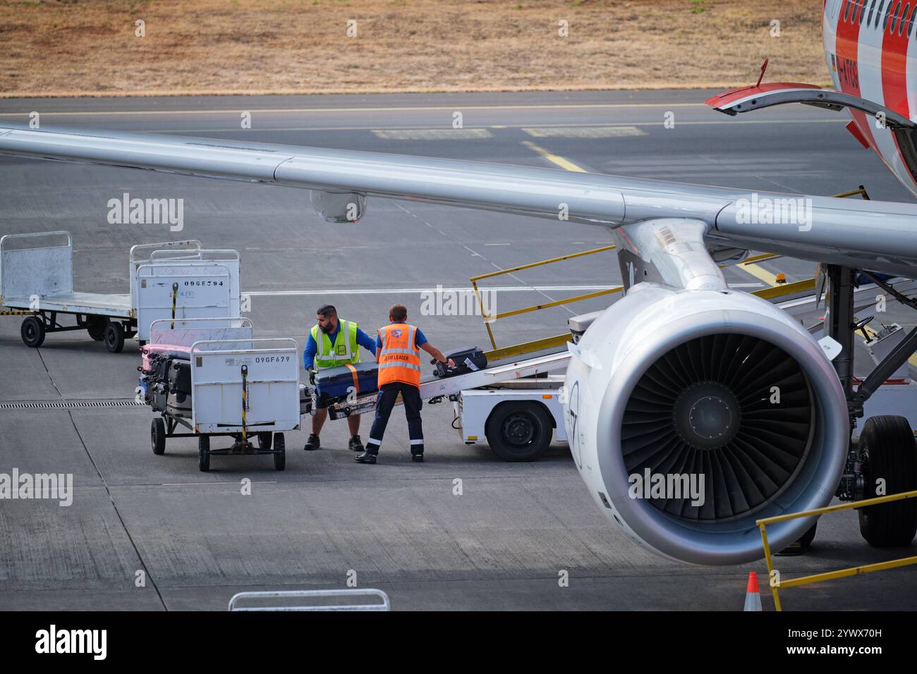 Airport ground crew man is loading luggage suitcases onto a plane from ...